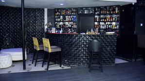 Uma área de bar com parede de pedra, banquetas e diversas garrafas.