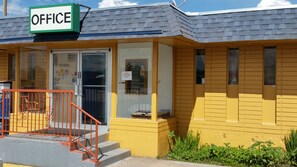 Um edifício amarelo com uma placa na entrada que diz 'OFFICE'.