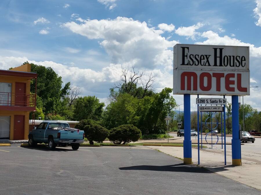 Placa de motel com vista clara da área de estacionamento e um edifício ao fundo.
