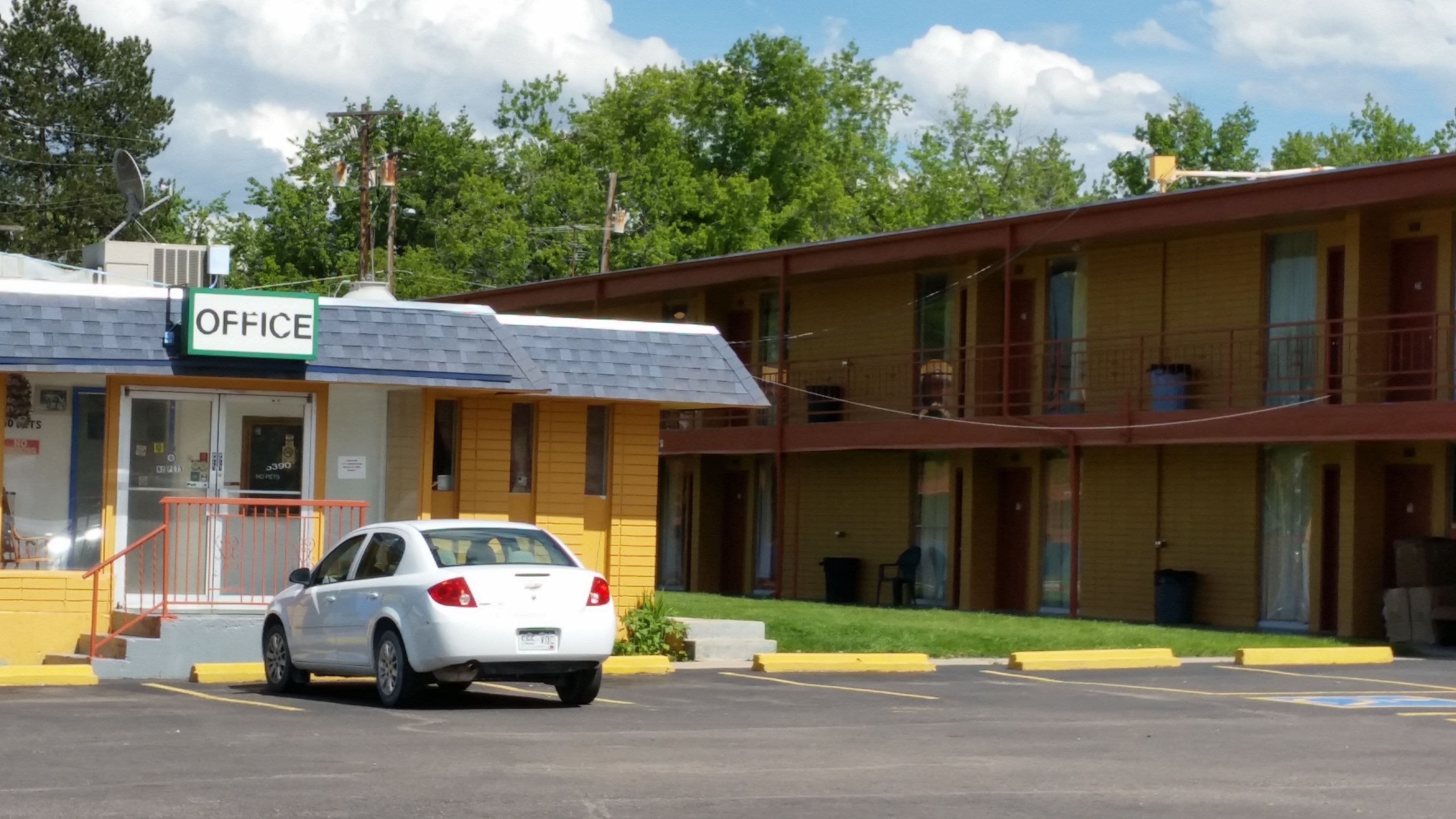 Um motel de dois andares com uma placa indicando "ESCRITÓRIO" no andar térreo.