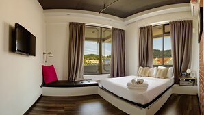 Quarto moderno com cama, janela com cortinas, televisão de tela plana e vista para o exterior.