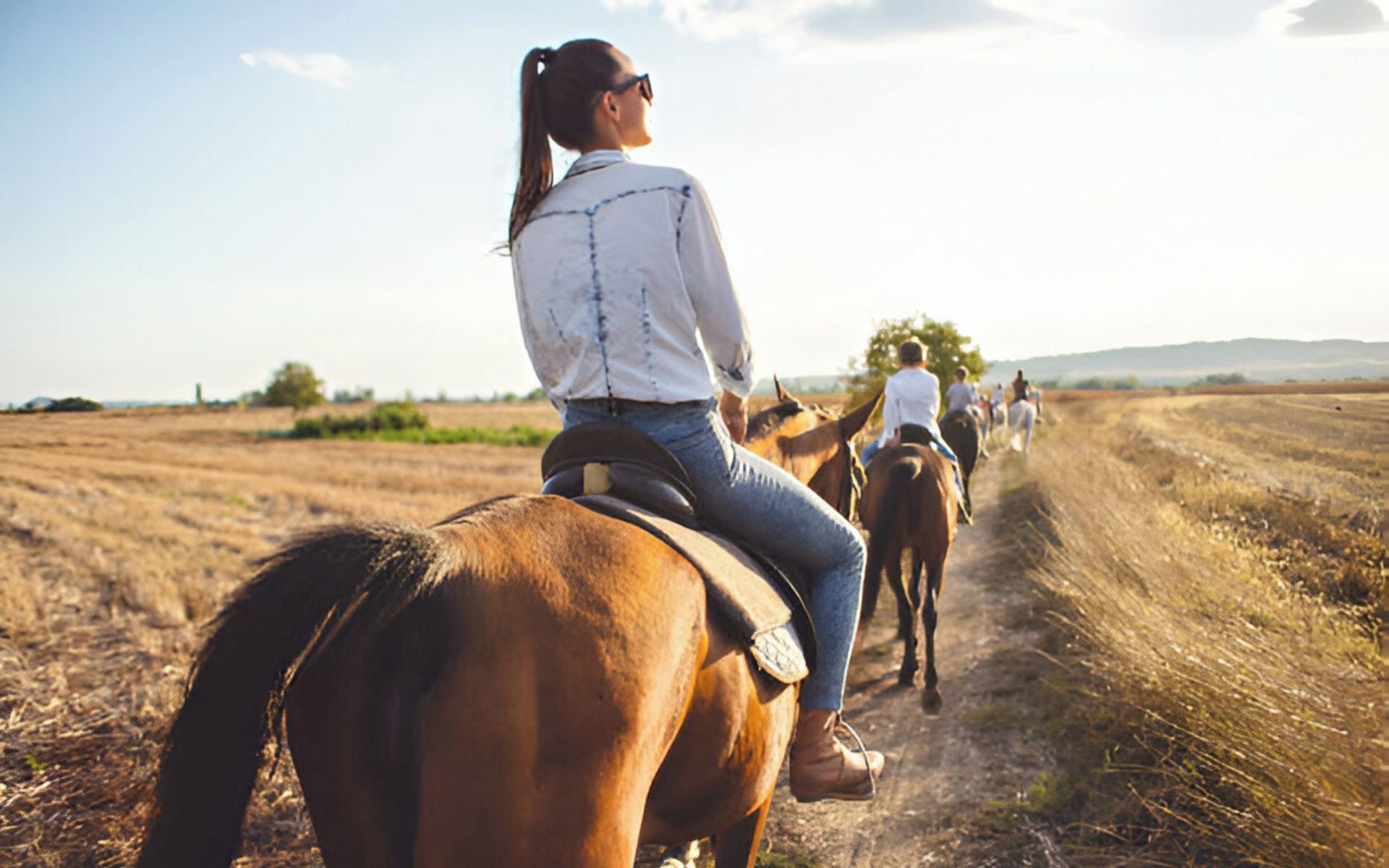 Uma pessoa a cavalo numa trilha de terra numa zona rural.