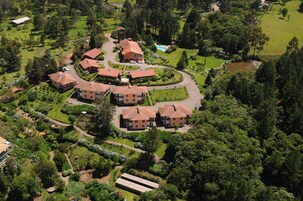 Vista aérea de uma área residencial com várias casas, uma piscina e jardins bem cuidados.