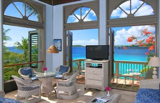 Quarto com televisão, mobiliário de vime e vista para o mar.