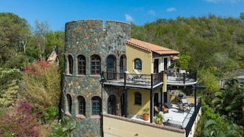 Um edifício de dois andares com uma torre de pedra e uma varanda com área de estar ao ar livre.