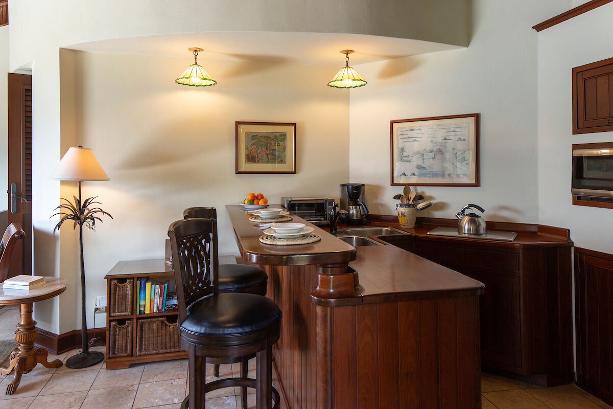 Uma cozinha com ilha de madeira, banquetas, cafeteira e quadros na parede.
