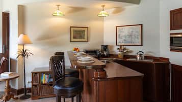 Uma cozinha com ilha de madeira, banquetas, cafeteira e quadros na parede.