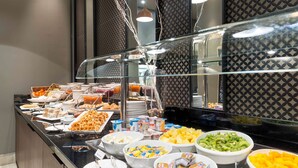 Buffet com diversas opções de comida, incluindo frutas, cereais e sobremesas.