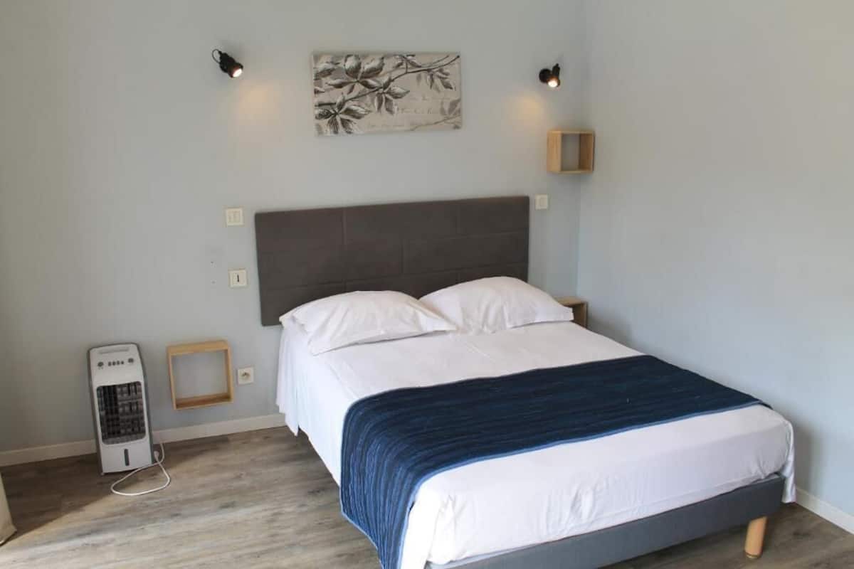 Quarto com cama, mesas de cabeceira, aquecedor e uma obra de arte na parede.
