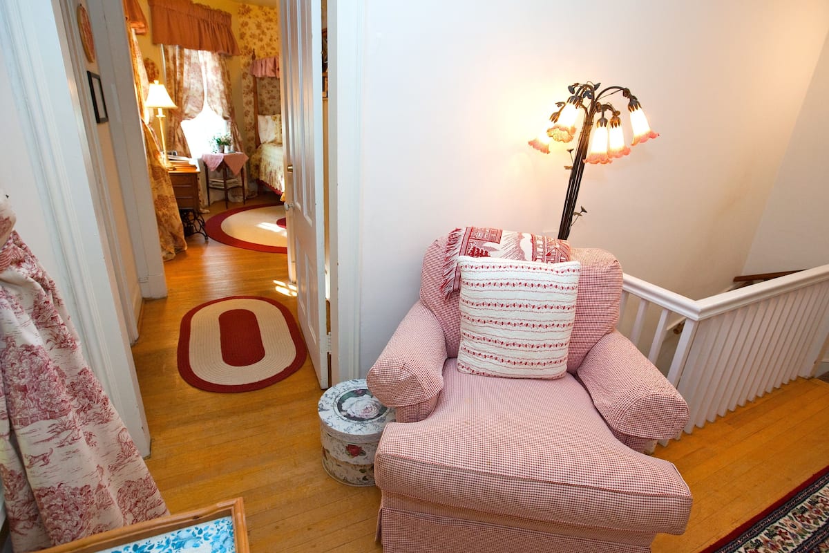 Um quarto aconchegante com uma poltrona rosa, um tapete redondo e uma luminária.