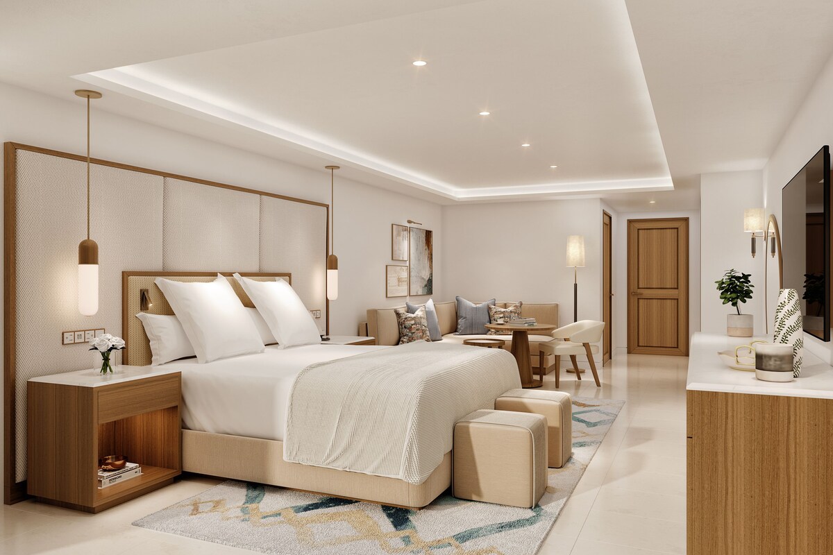 Um quarto moderno com uma cama grande, mesas de cabeceira, uma escrivaninha e uma televisão.