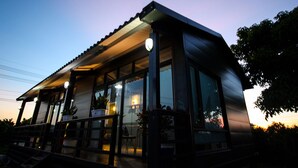 Uma casa moderna com amplas janelas, varanda coberta e interior bem iluminado.