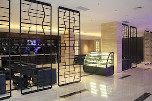 Um lobby moderno com uma vitrine de vidro, áreas de estar e um bar.