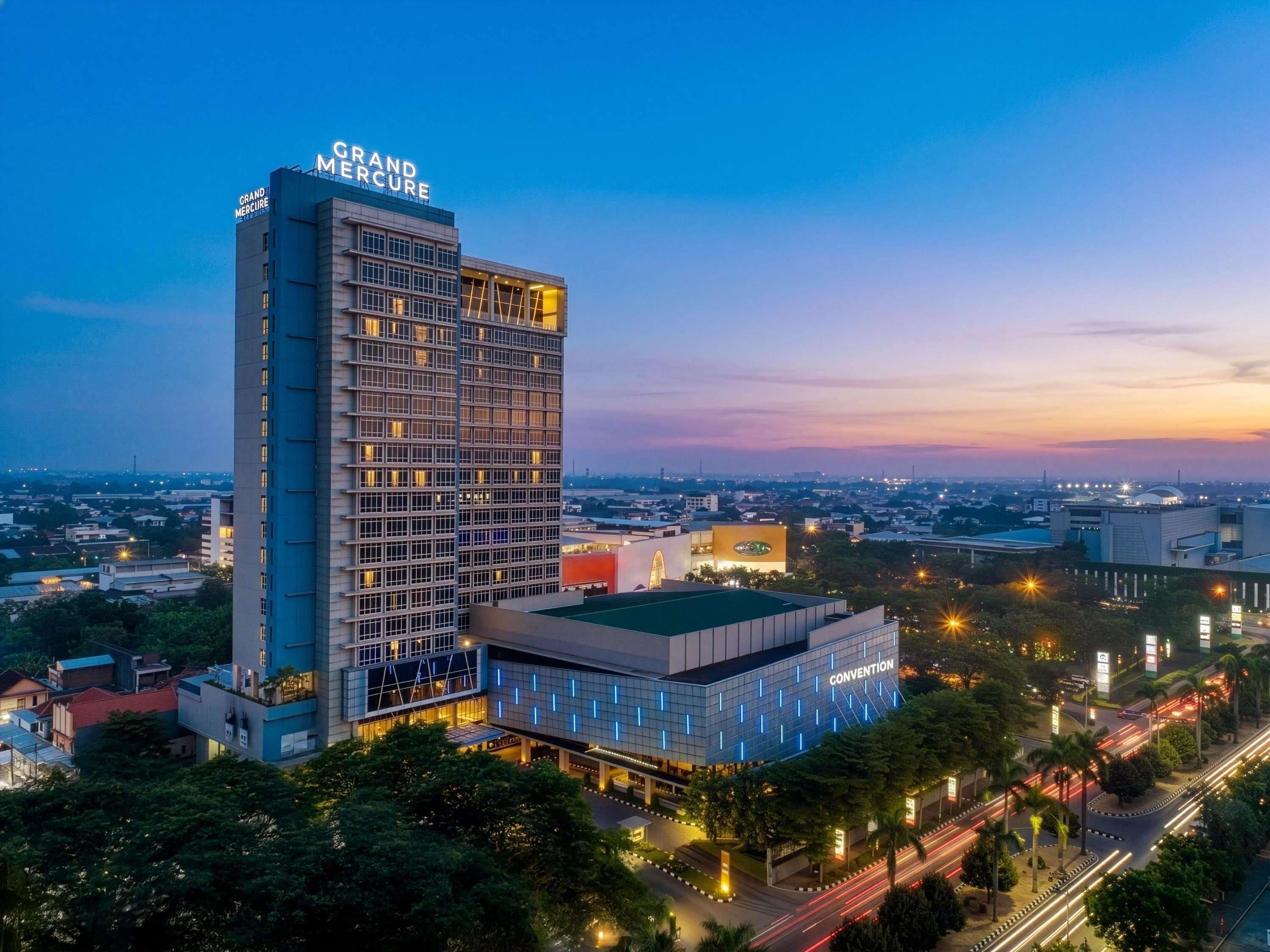Um hotel imponente com um letreiro grande que diz 'Grand Mercure' no topo.