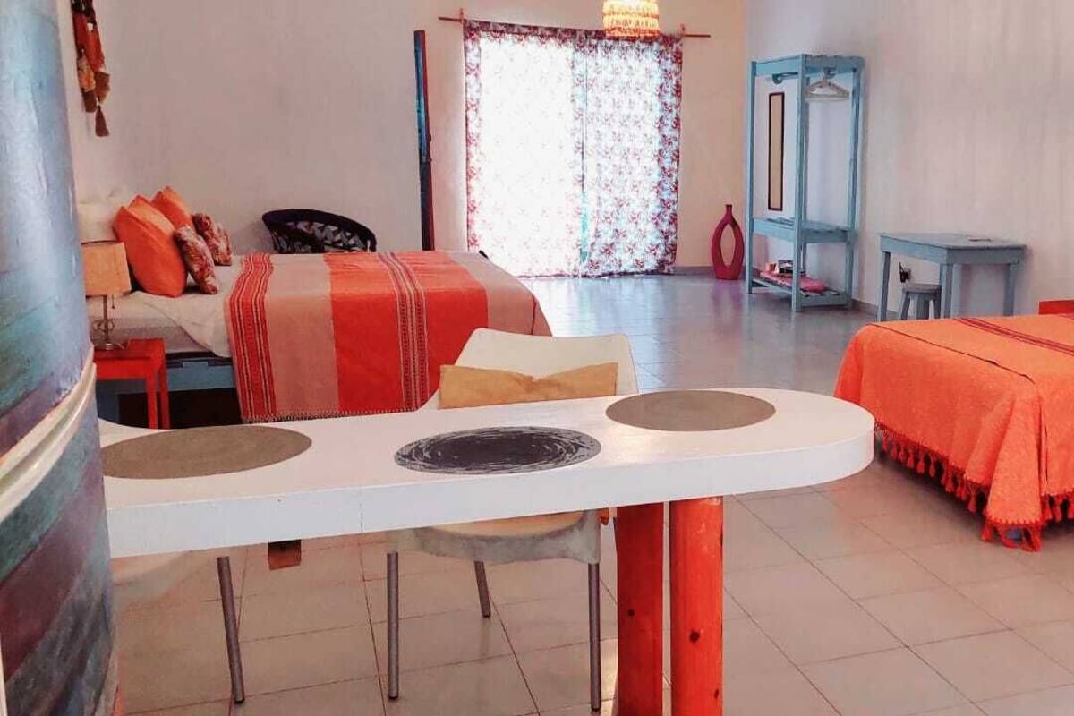 Quarto de hotel com cama, mesa de jantar, cadeira, mesinha e guarda-roupa.