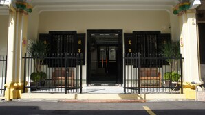 Entrada de hotel com portão preto, pilares amarelos e telhado telhado.