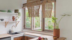 Cozinha com bancada de madeira, pia e janela com vista para o verde.