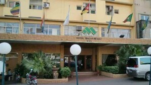 Um hotel com várias bandeiras, fachada de tijolos e área de estacionamento com carros.