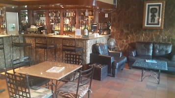 Uma área de bar com parede de pedra, assentos de couro e diversos tipos de bebidas.