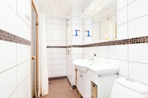 Casa de banho moderna com azulejos brancos, lavatório branco e sanita.