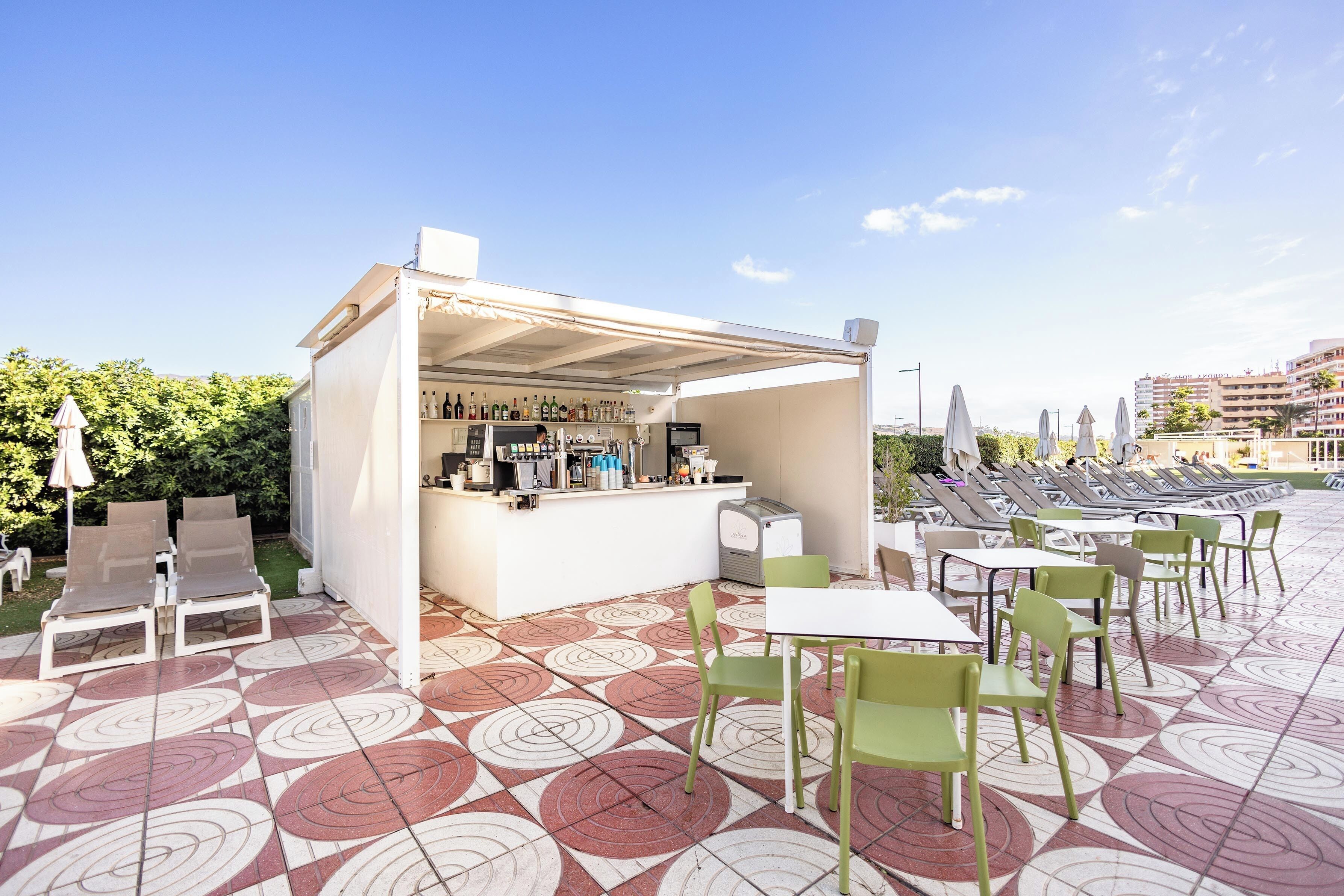 Uma área de bar ao ar livre com balcão, cadeiras e mesas.