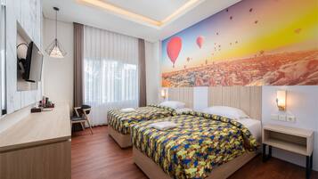 Quarto de hotel com duas camas, uma secretária de madeira, uma cadeira, uma televisão e um mural com balões de ar quente.