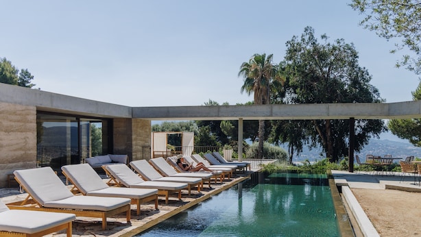 Área da piscina com espreguiçadeiras e vista para a paisagem.