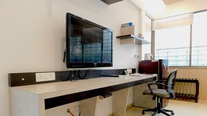 Um espaço de escritório moderno com uma grande televisão de tela plana presa à parede, uma escrivaninha com cadeira e um radiador no chão.