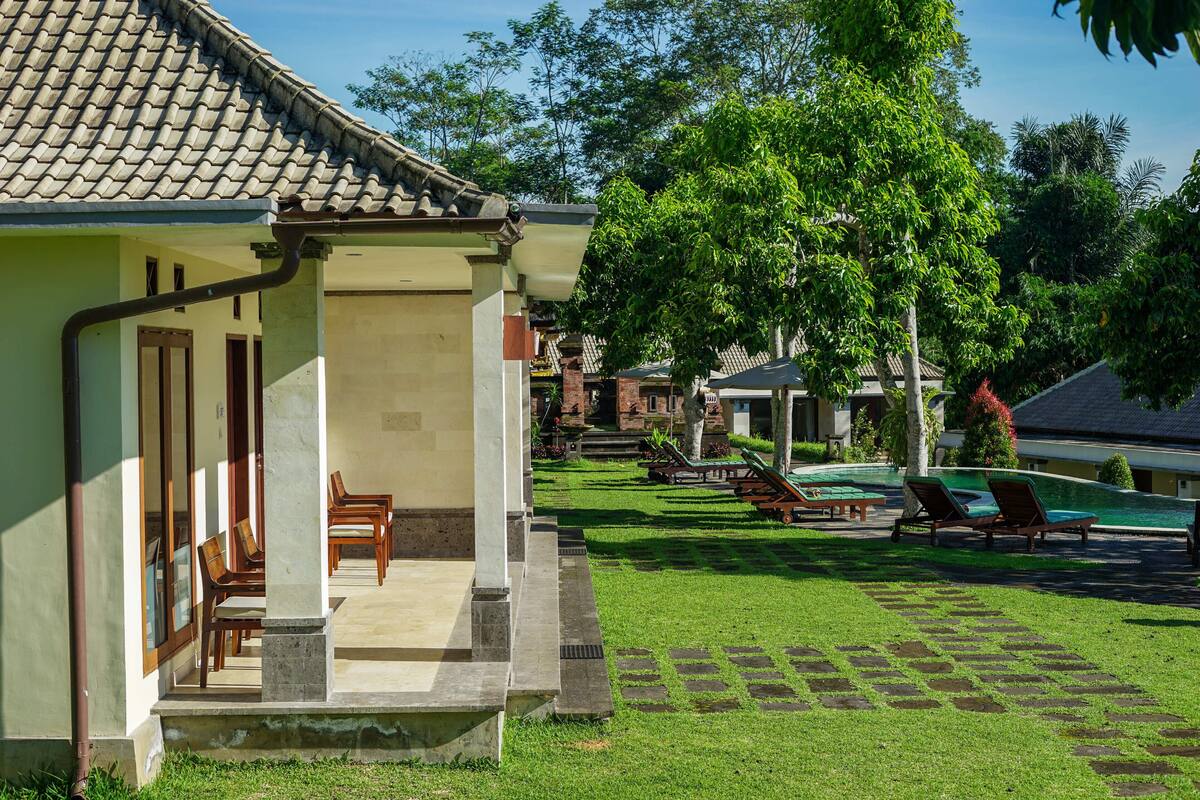 Uma vila tradicional com telhado de azulejos, piscina e um jardim bem cuidado com espreguiçadeiras.