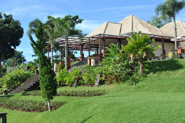 Um resort com área externa coberta, palmeiras e um jardim bem cuidado.