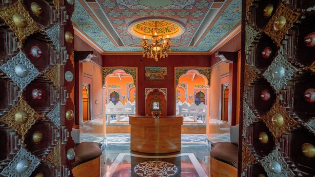 Um interior luxuoso, com decorações requintadas, um lustre central e um chão espelhado.