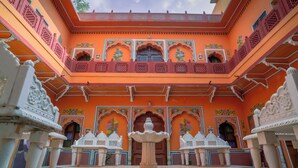 Um pátio com arcos ornamentados, uma fonte central e uma varanda com grades elaboradas.
