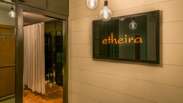Interior de hotel com design moderno, apresentando uma placa com o nome 'etheira' e um espelho refletindo o ambiente.