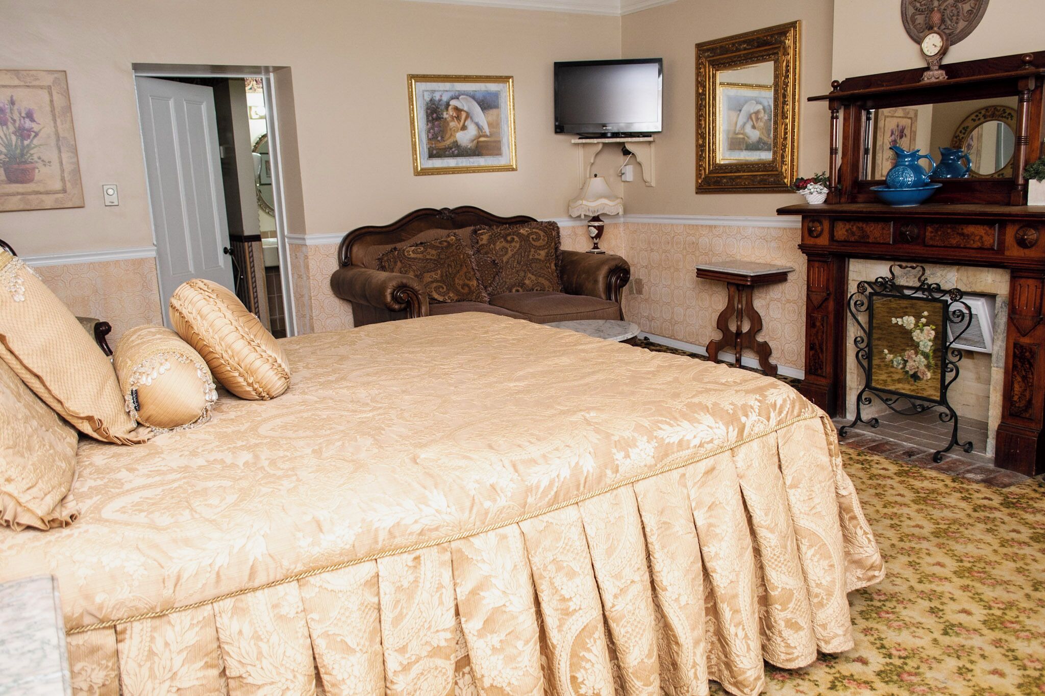 Quarto com cama grande, televisão, lareira e espelho.