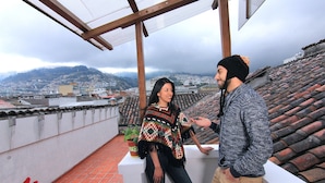 Terraço no telhado com vista para a paisagem urbana e montanhas.