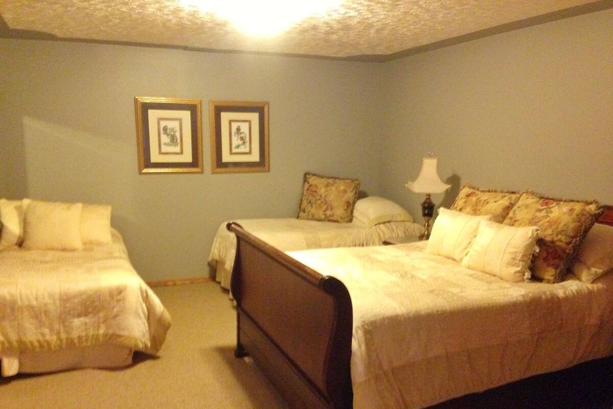 Quarto com duas camas de solteiro, cabeceira de madeira, mesa de cabeceira e abajur.