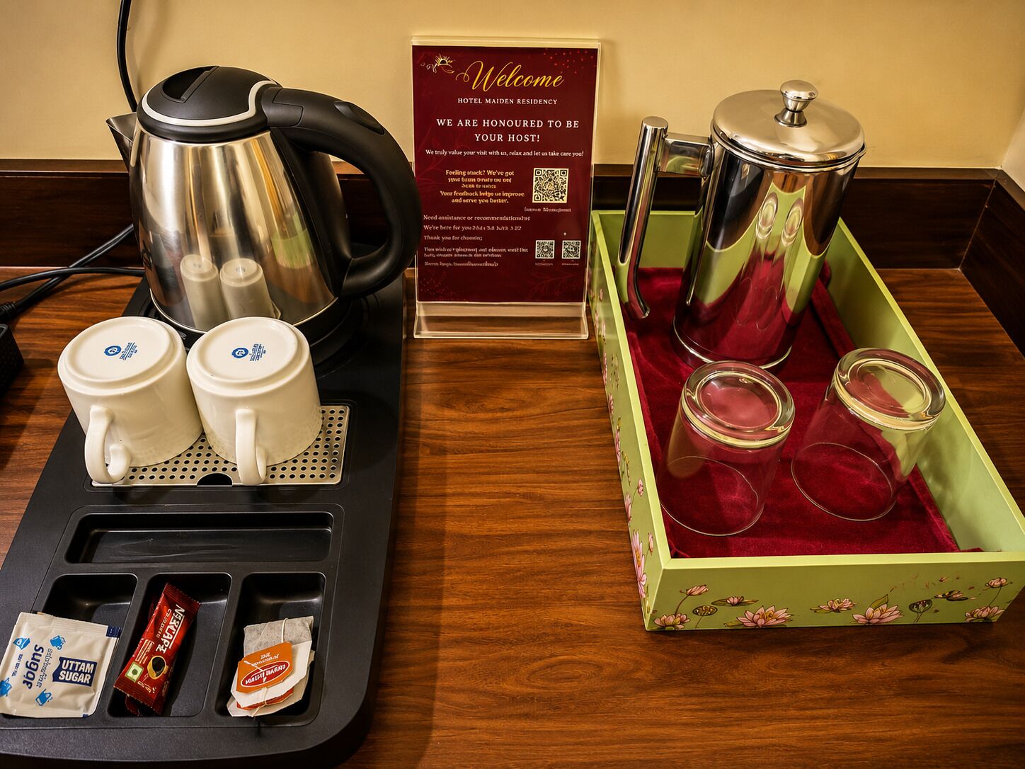 Disposição para o café da manhã em um quarto de hotel, incluindo uma cafeteira, bule de chá, xícaras, sachês de açúcar e uma caixa de chá.