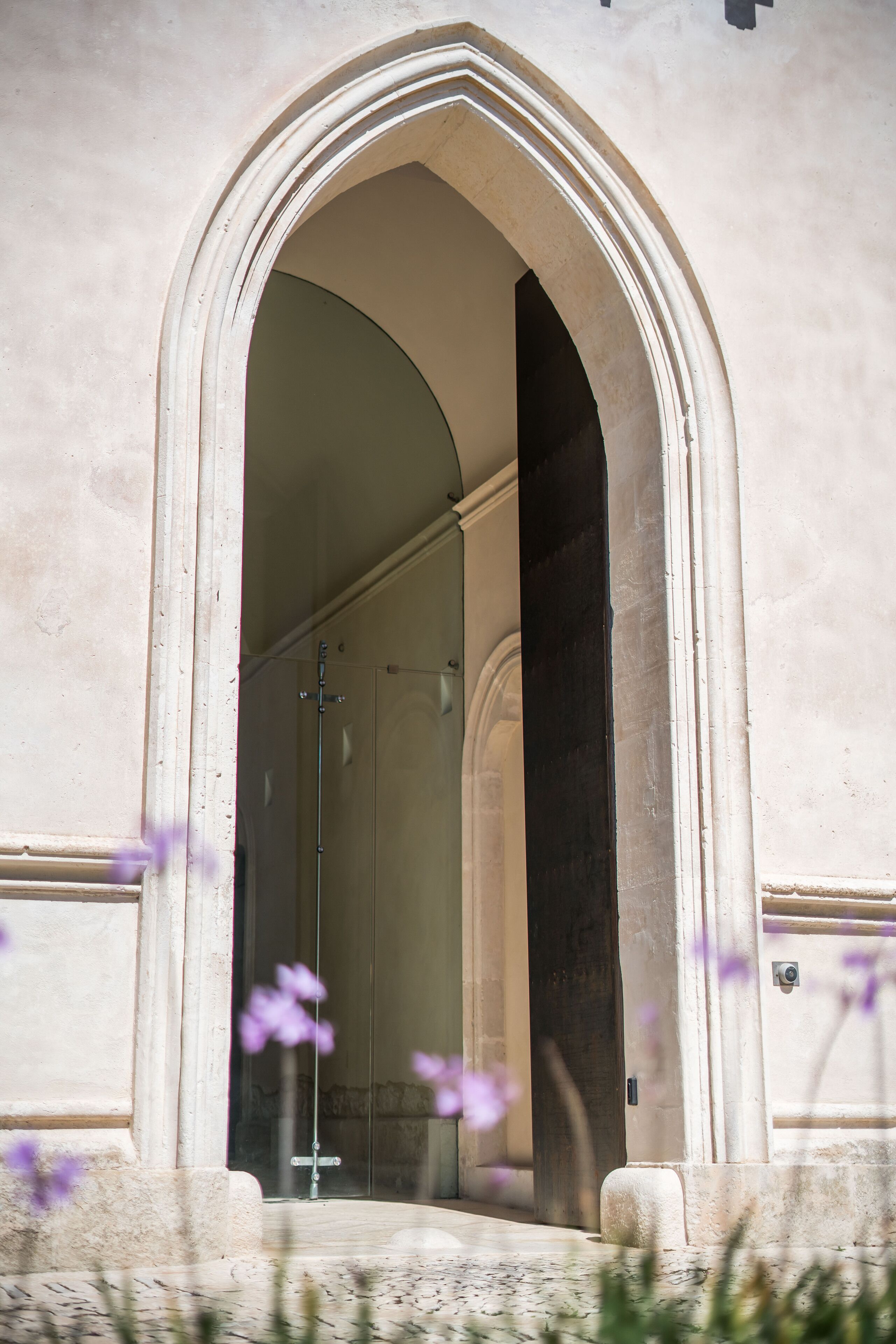 Uma porta arqueada que dá para um quarto com uma porta de vidro e um chuveiro.