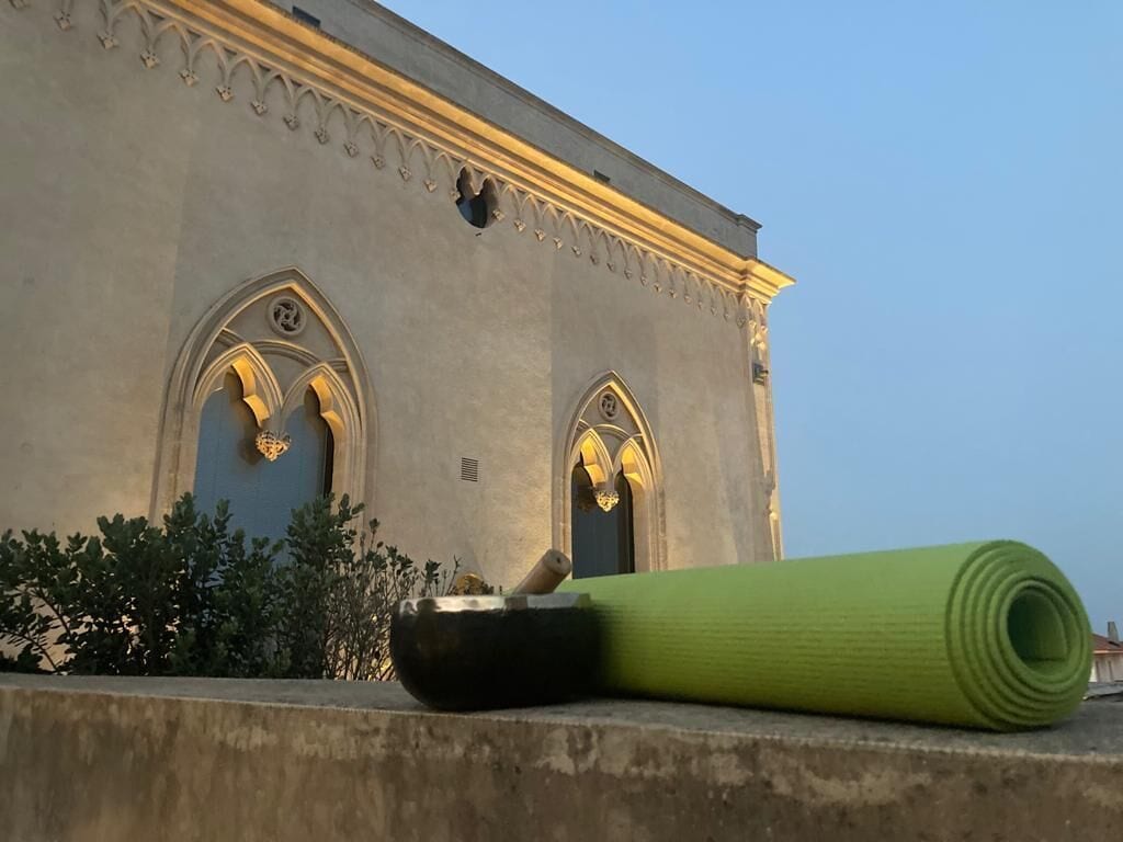 Um edifício com janelas em arco e um tapete verde enrolado no chão.