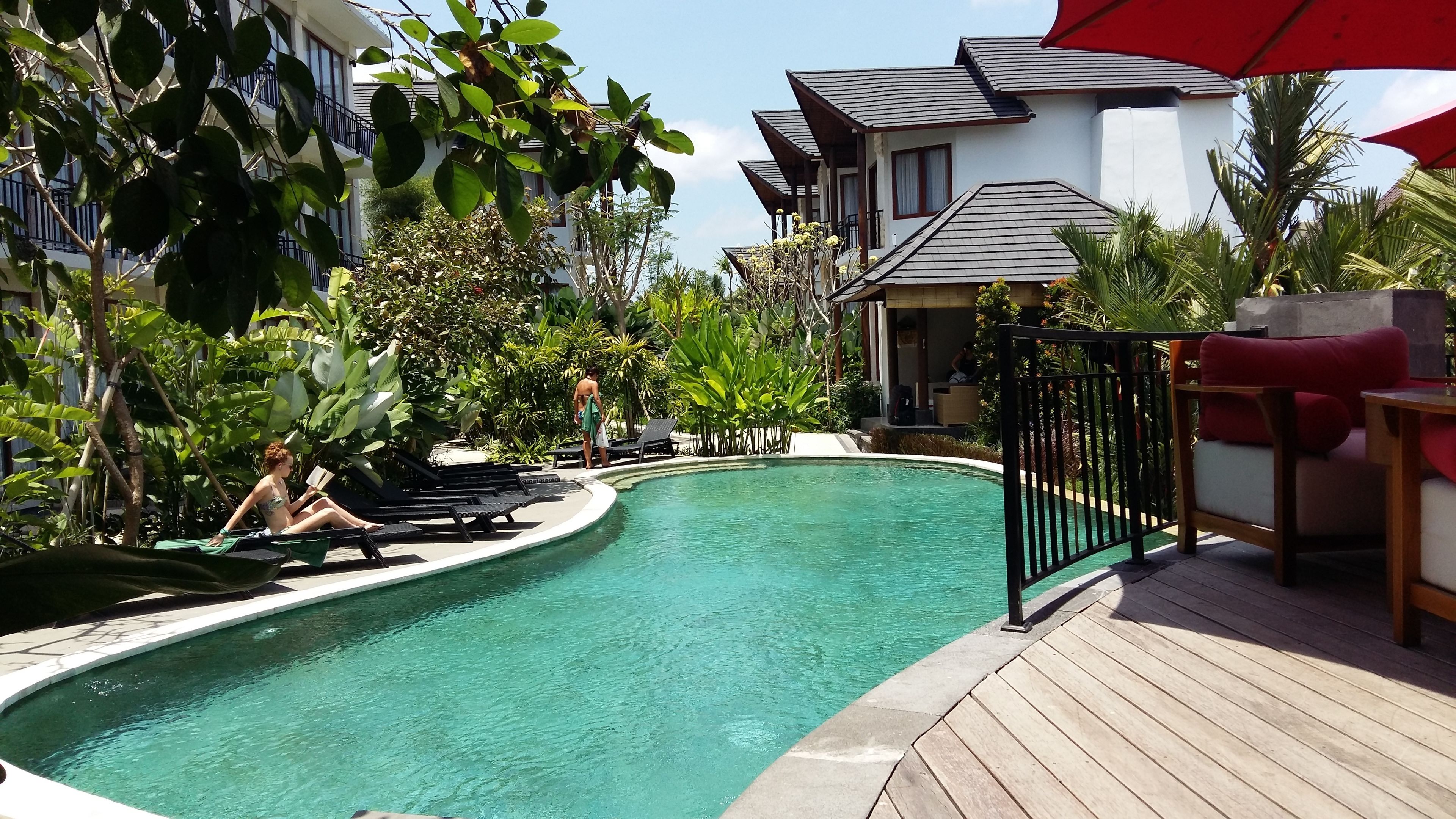 Piscina com espreguiçadeiras e deck de madeira.