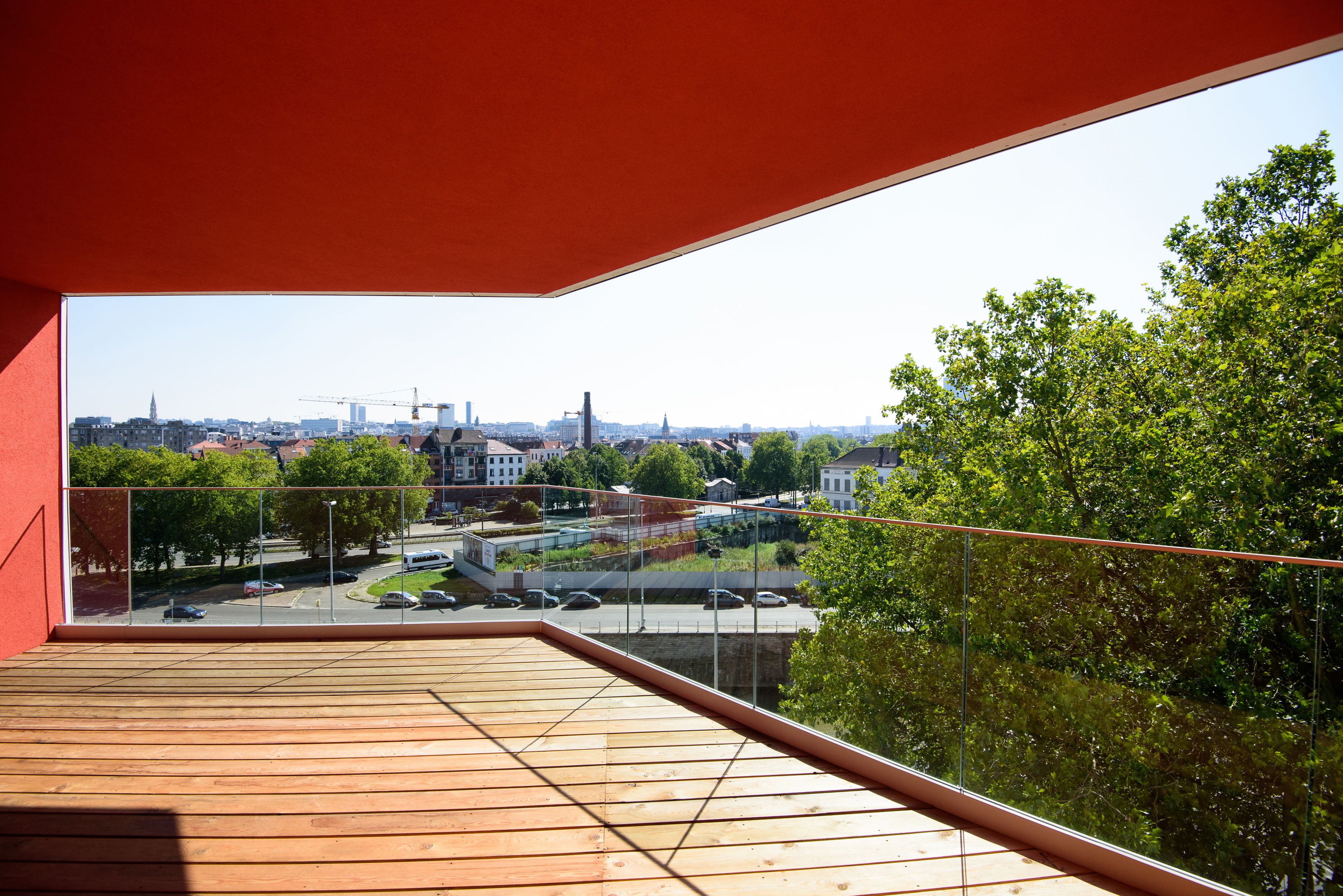 Uma varanda moderna com vista desobstruída para o horizonte urbano, incluindo edifícios e árvores.