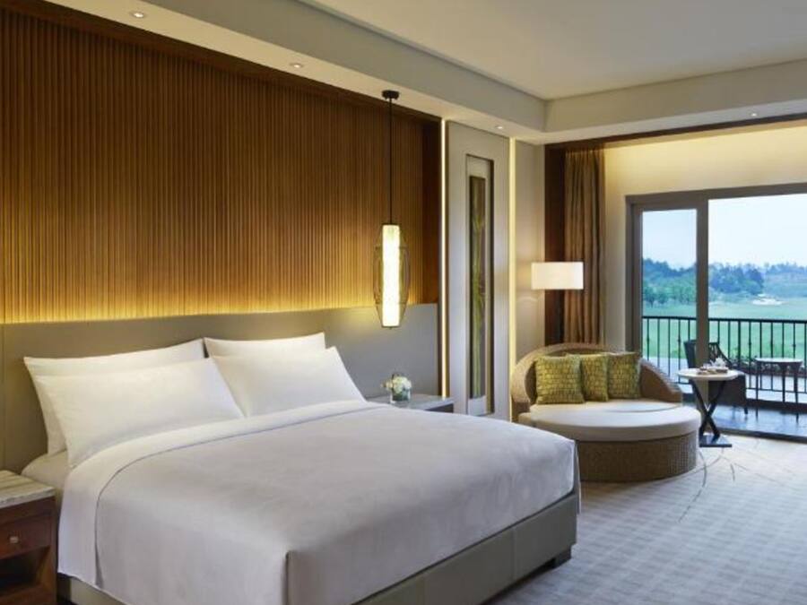 Quarto de hotel com uma cama grande, área de estar com vista e varanda.