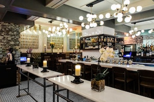 Uma área de bar com diversas opções de assento, balcão e variedade de garrafas e copos.