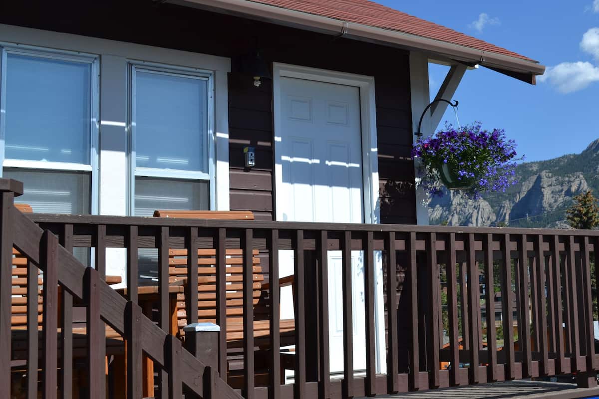 Uma casa com telhado vermelho, portas de garagem brancas e um deck de madeira.