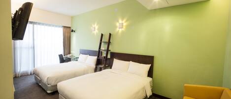 Quarto de hotel com duas camas, uma escrivaninha, uma cadeira e uma TV fixada na parede.