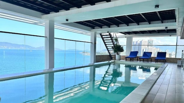 Piscina infinita interna com vista clara para o mar e o horizonte da cidade.