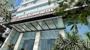 Um hotel moderno com fachada de vidro, uma placa chamativa com a inscrição 'HONDERLAND HOTEL' e uma vista desimpedida do céu.