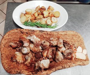 Um prato de batatas assadas e uma tábua de madeira com carne e batatas.