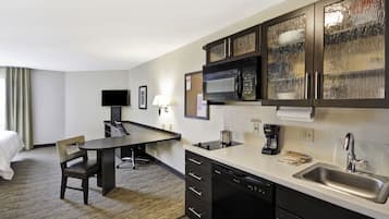 Quarto de hotel compacto com cozinha compacta, área de refeições e uma cama.