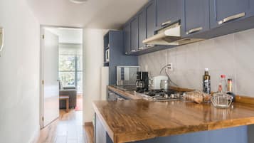 Cozinha moderna com armários azuis, bancada de madeira e vista para uma varanda.